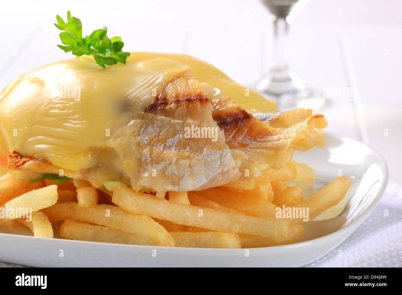 Cheese topped fish fillets served with French fries Stock Photo - Alamy