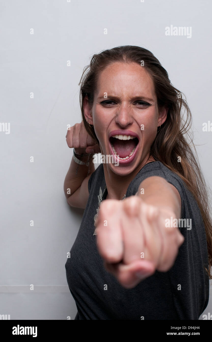 A hip and trendy young woman throws a punch on white background Model ...