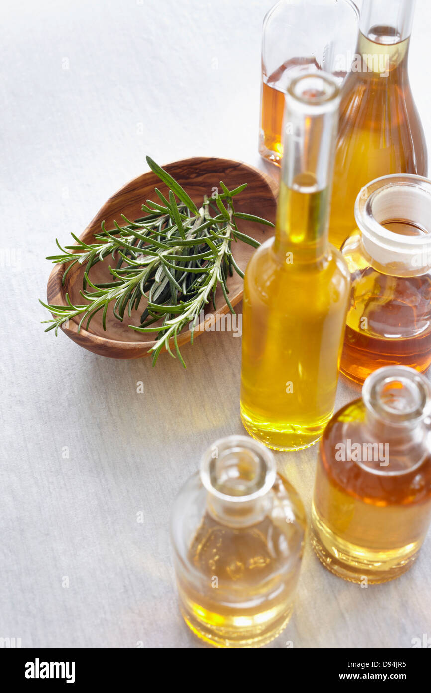 Sprig of rosemary in a bowl, herbs and bottles of oil Stock Photo - Alamy