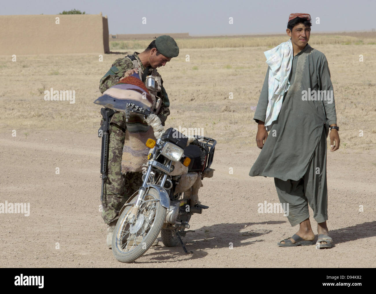 An Afghan Army soldier stops to search a villagers motorcycle at a ...