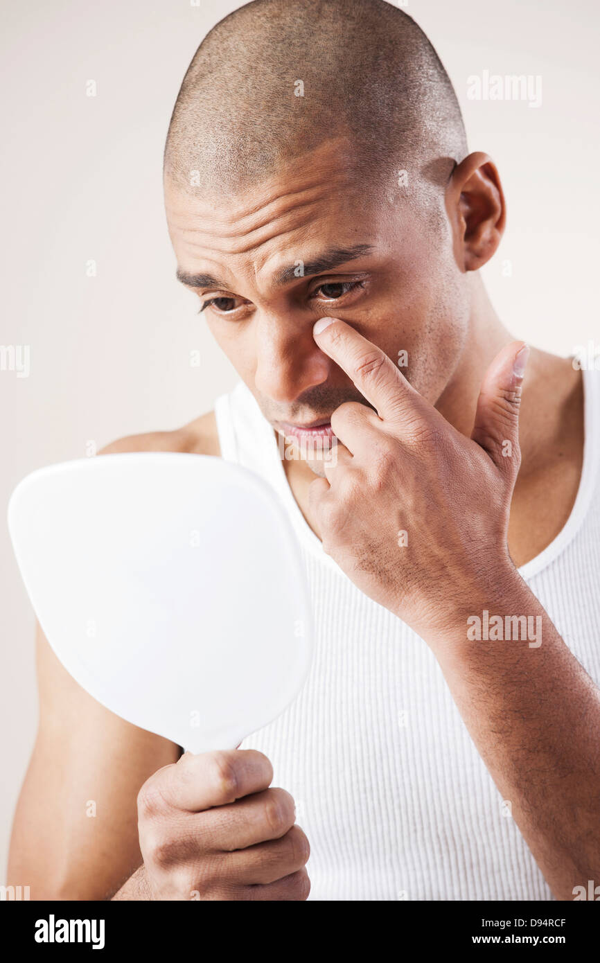 Man Looking at his Face in a Mirror in Studio with White Background ...