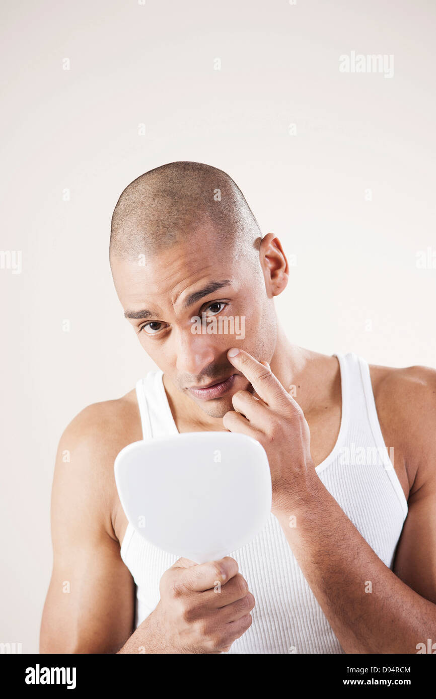 Man Looking at his Face in a Mirror in Studio with White Background ...