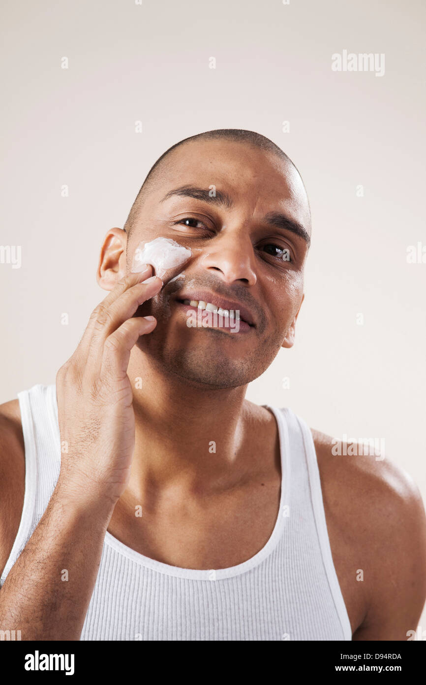 Man Applying Lotion to his Face in Studio with White Background Stock ...