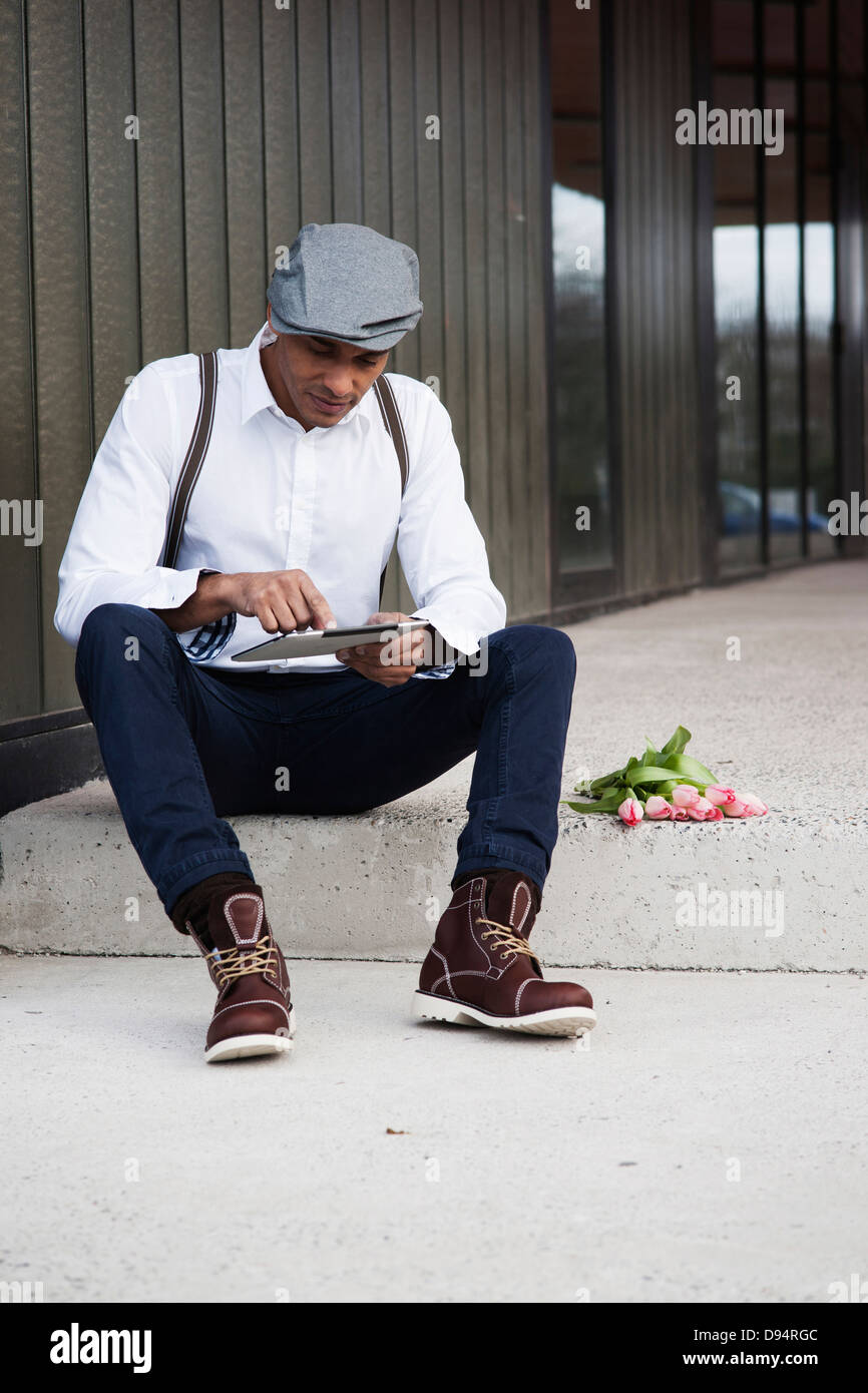 Portrait of Man Sitting on Step with Flowers, Using a Tablet, Mannheim ...