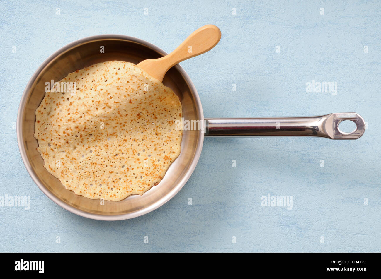 Overhead View of Pancake in Frying Pan with Spatula on Blue Background ...