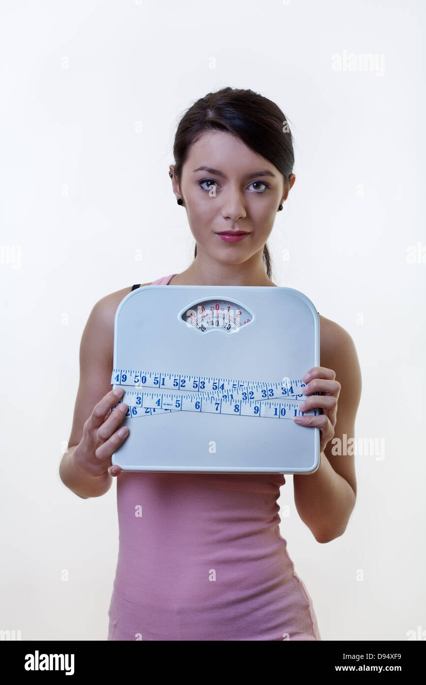 attractive woman holding scales with a tape measure wrapped around them ...