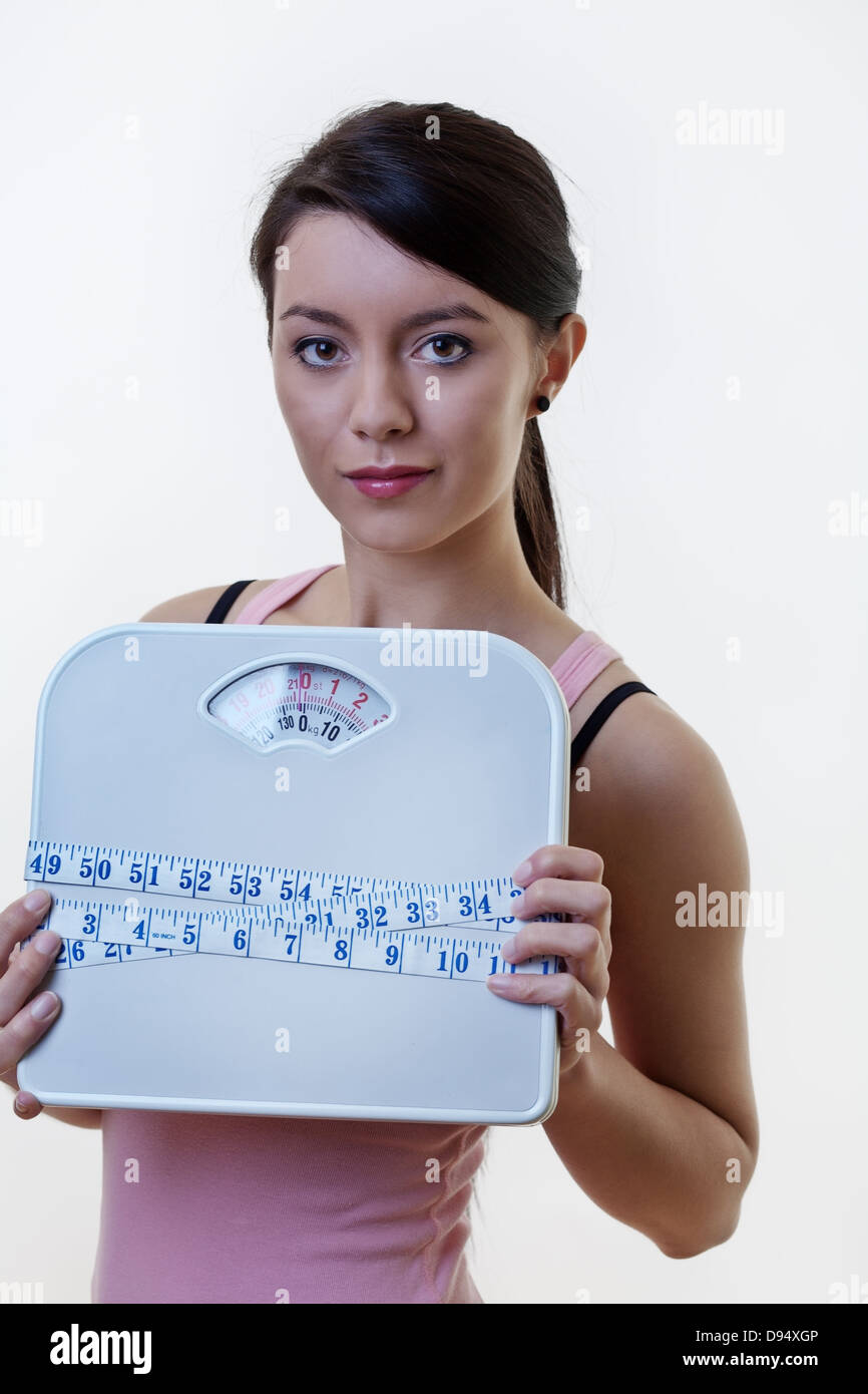 attractive woman holding scales with a tape measure wrapped around them ...