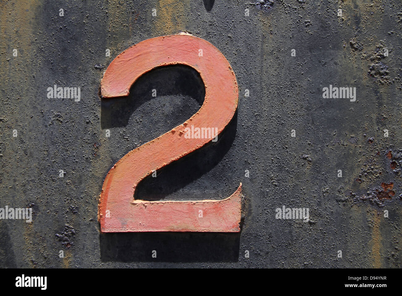 a number 2 two made of steel that is a faded red color mounted on a ...