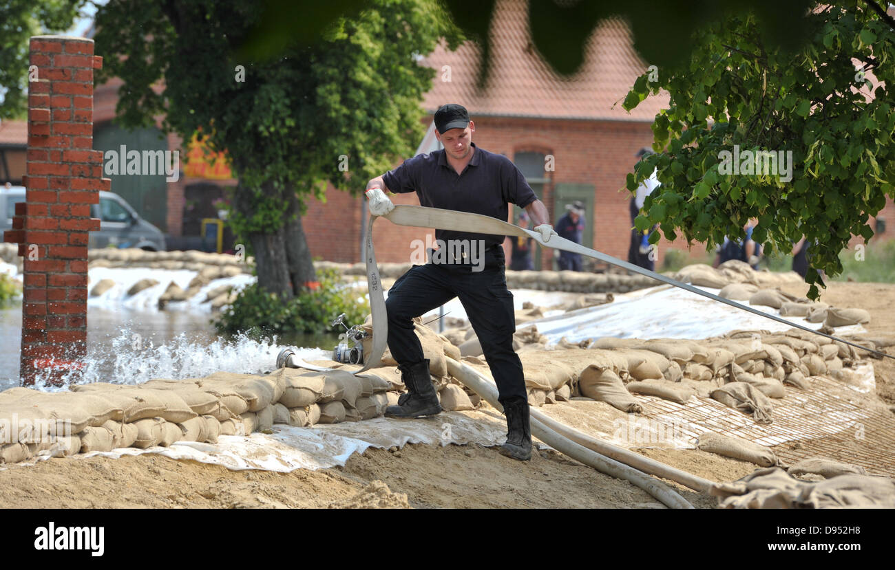 A fire fighter lays a hose into a dike made of sandbags in Neu Darchau ...