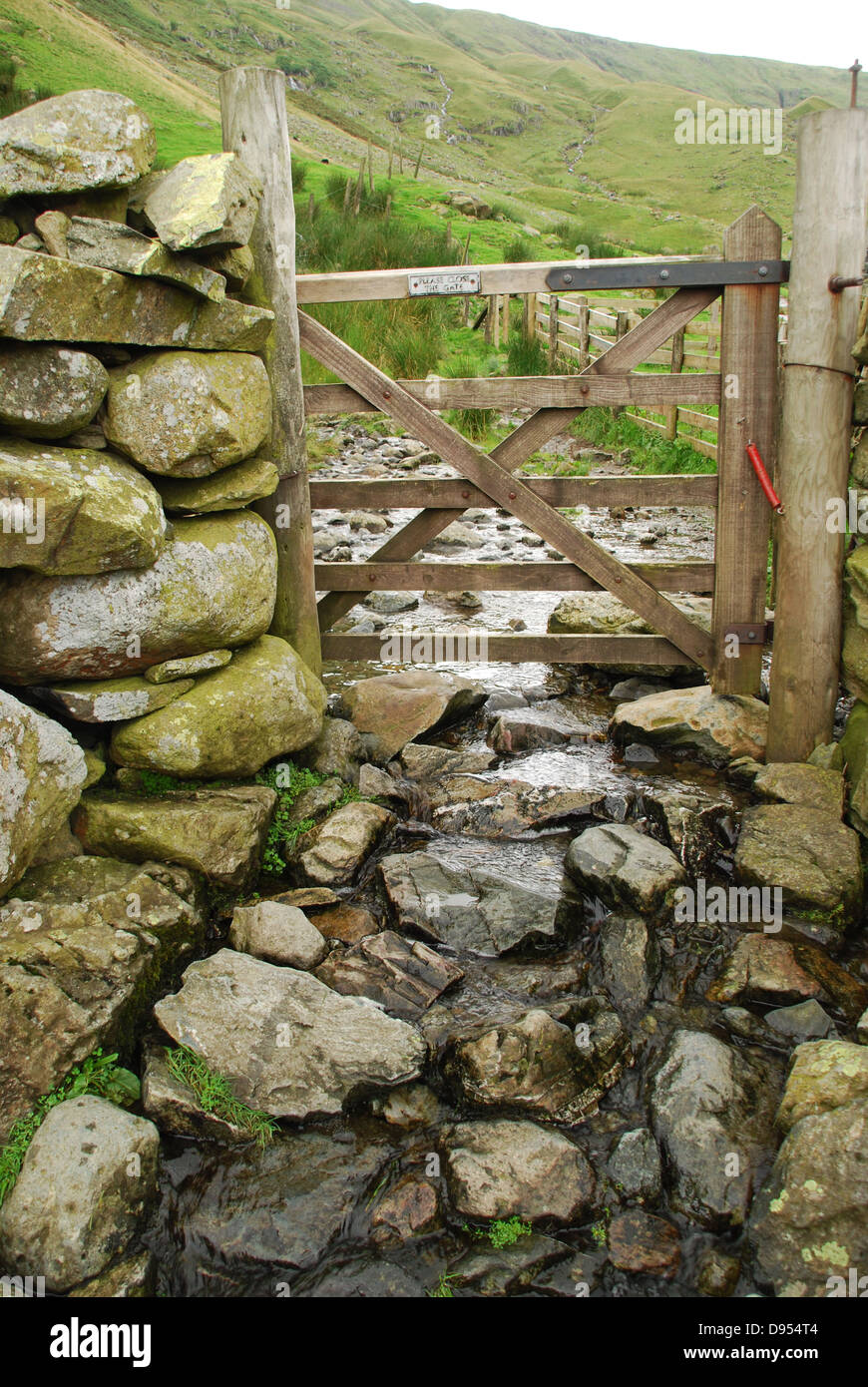 A gate on a path with a strem running down it. Lake District. Cumbria ...