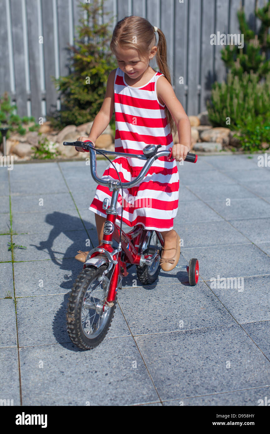 Little cute girl rides a bicycle in the dress in the yard Stock Photo ...