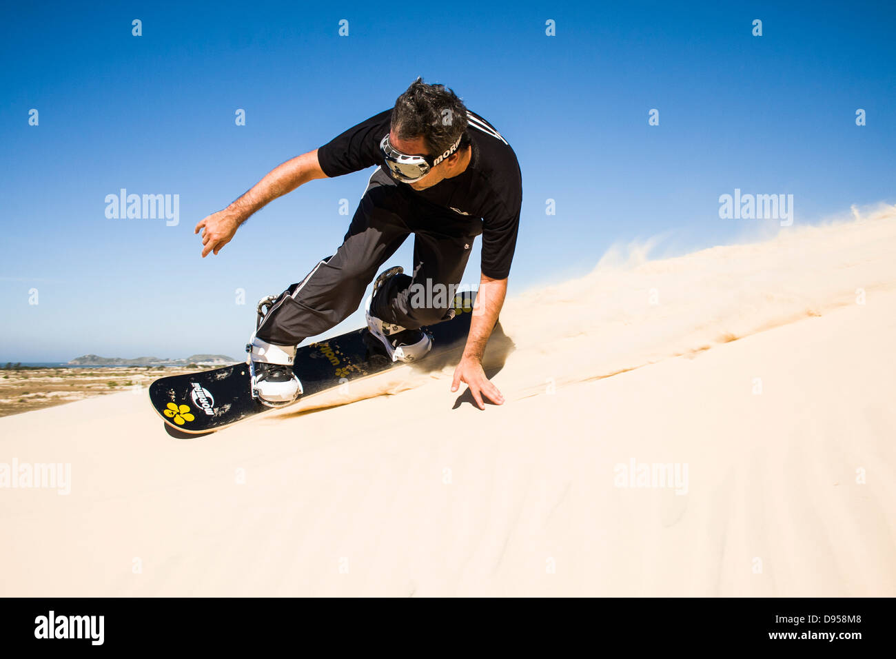 Adult man sandboarding on the dunes of Itapiruba Beach Stock Photo - Alamy