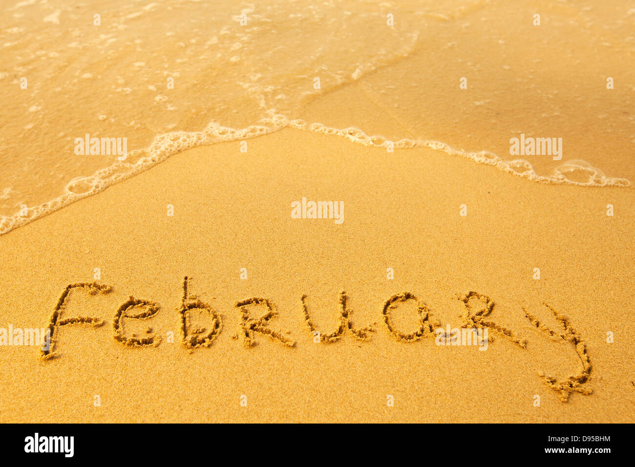 February - written in sand on beach texture, soft wave of the sea Stock ...