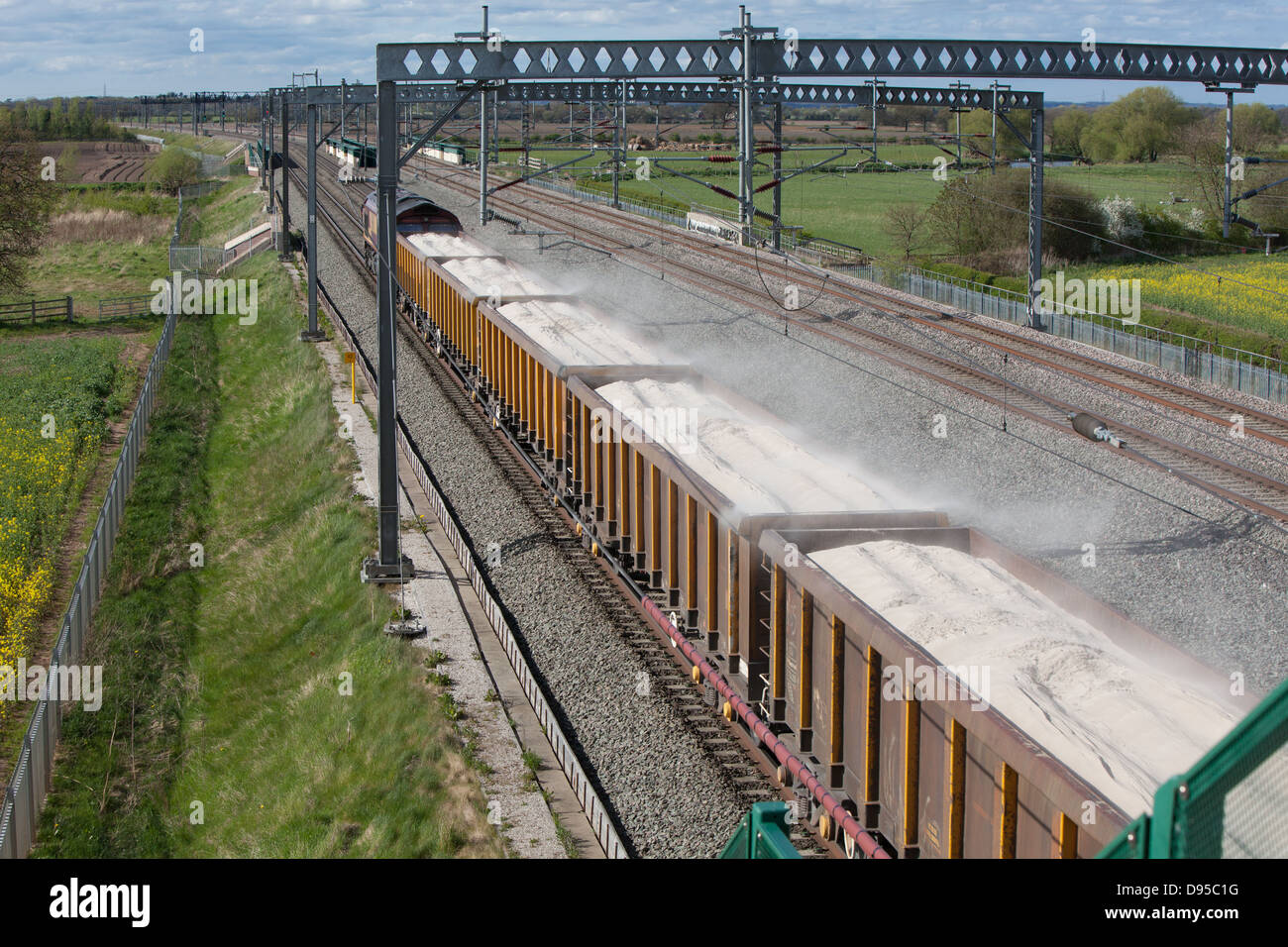 A cargo of sand blows from the back of a freight train on the West ...