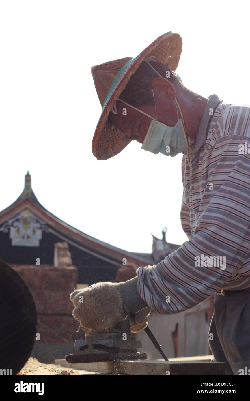 A worker works on old traditional houses being restored and a house ...