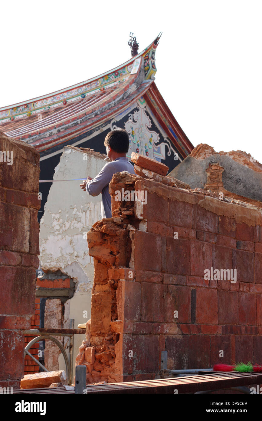 A worker works on old traditional houses being restored and a house ...