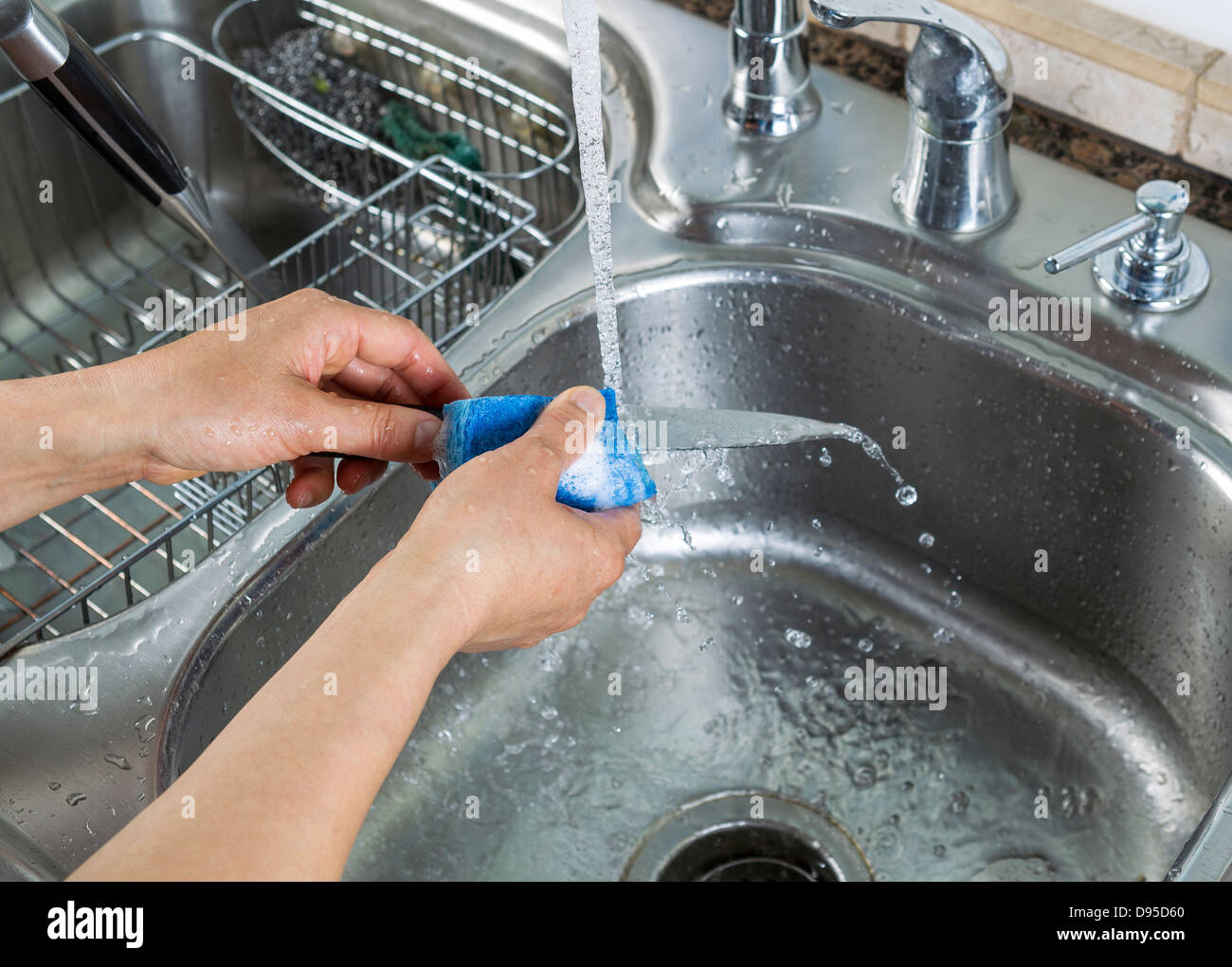 Horizontal photo of female hands washing a small knife with a soapy ...