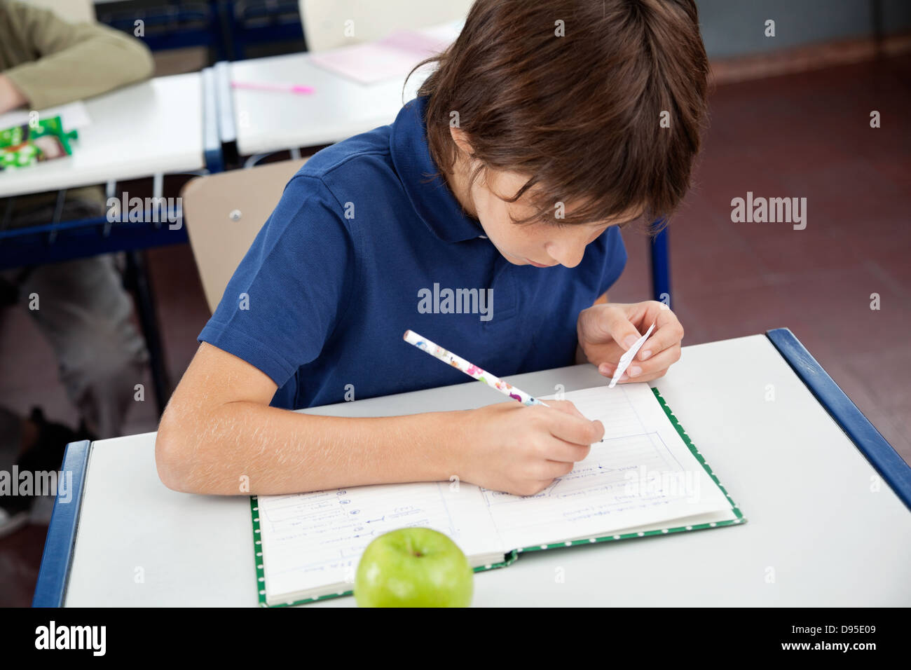 High angle view of little boy copying from cheat sheet at desk during ...