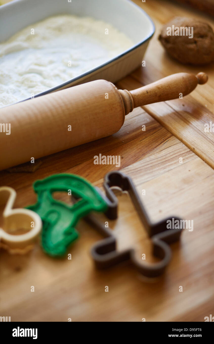 rolling pin with cookie cutters on a cutting board with white flour to ...