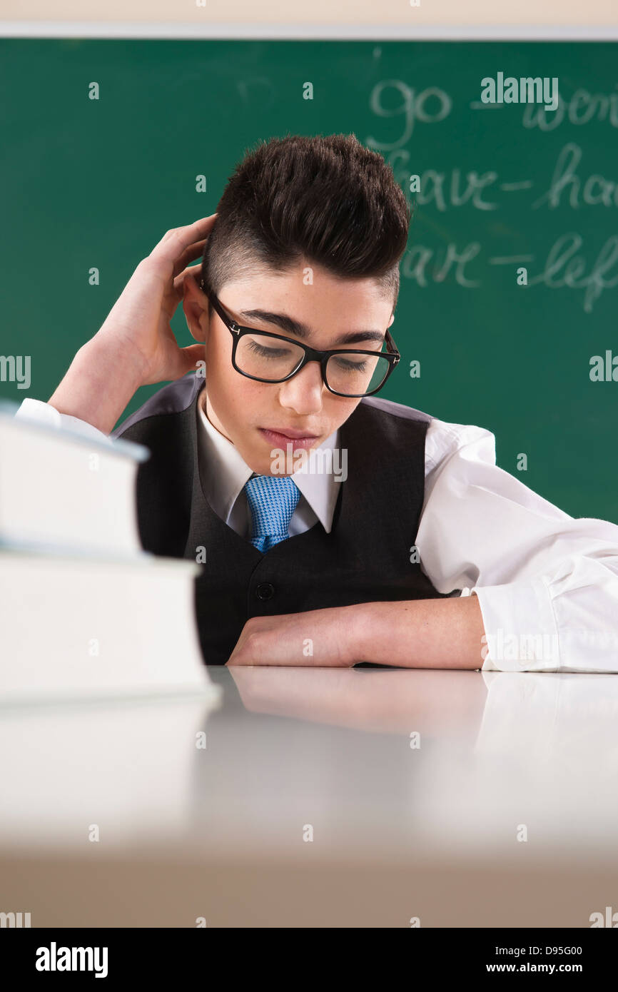 Boy Looking Down in front of Chalkboard in Classroom Stock Photo - Alamy