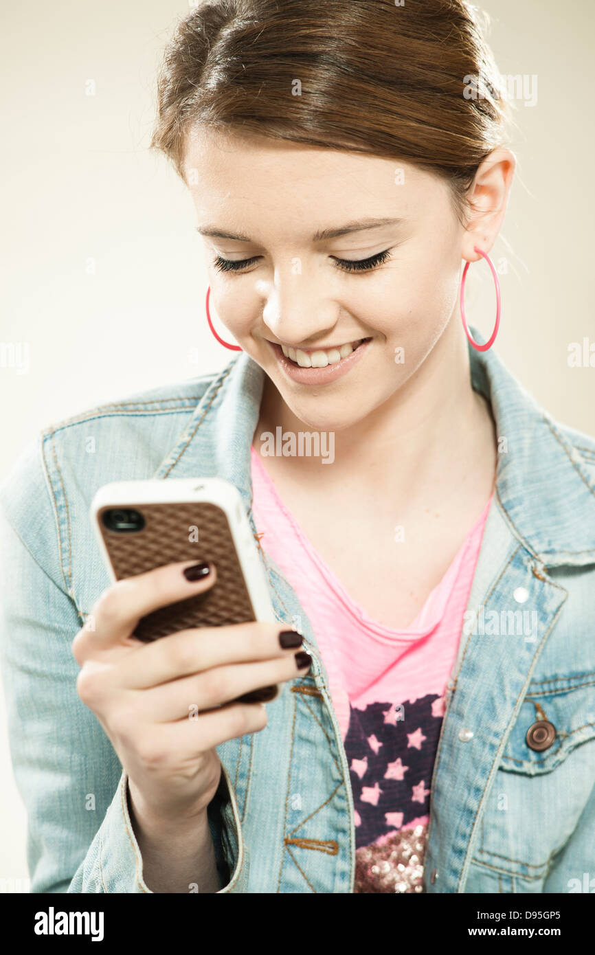 Portrait of Teenage Girl Reading Text Message on a Cell Phone in Studio ...