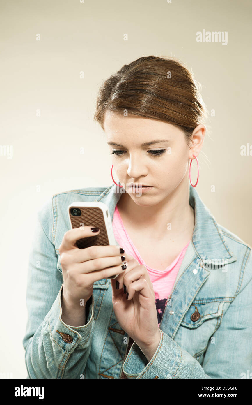 Portrait of Teenage Girl Reading Text Message on a Cell Phone in Studio ...
