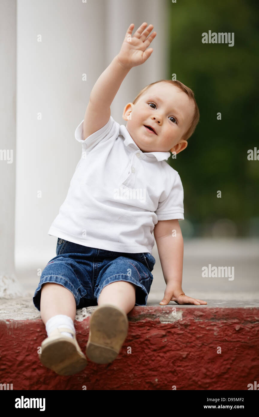 cute little boy with hand raised Stock Photo - Alamy