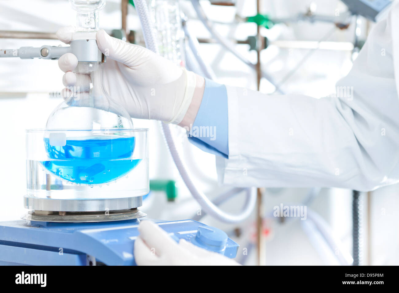 Germany, Young scientist setting up experiment with flask and condenser ...
