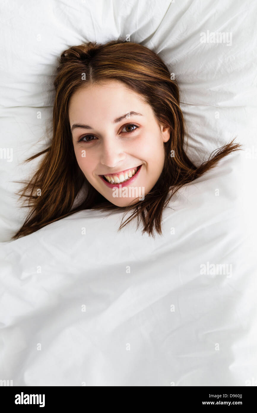 Portrait of young woman lying on bed, smiling Stock Photo - Alamy