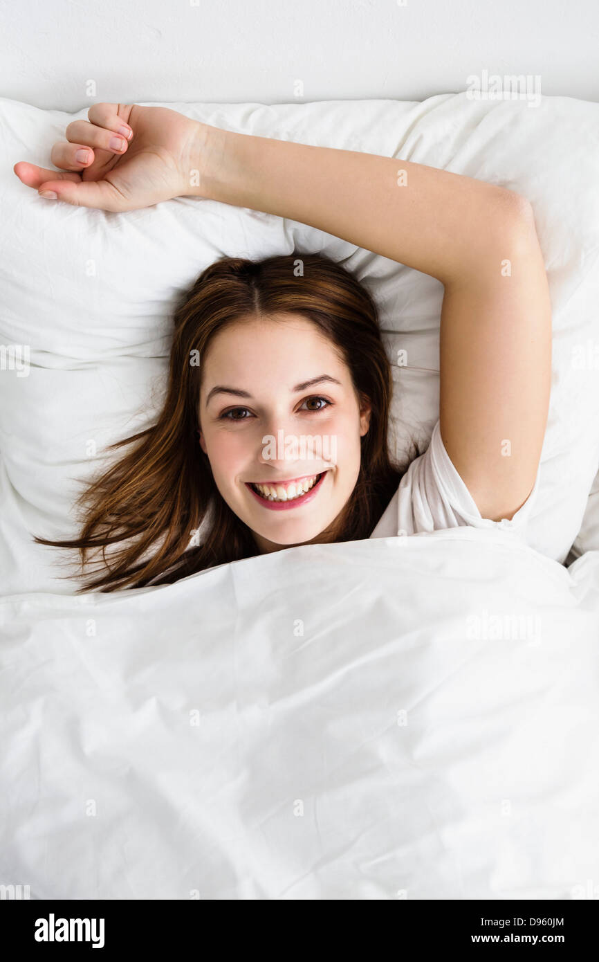 Portrait of young woman lying on bed, smiling Stock Photo - Alamy