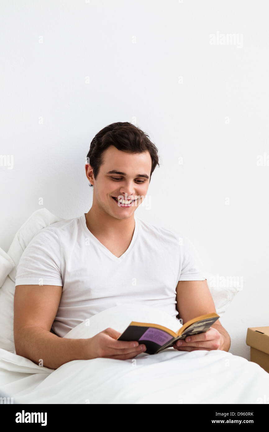 Young man reading book, smiling Stock Photo - Alamy