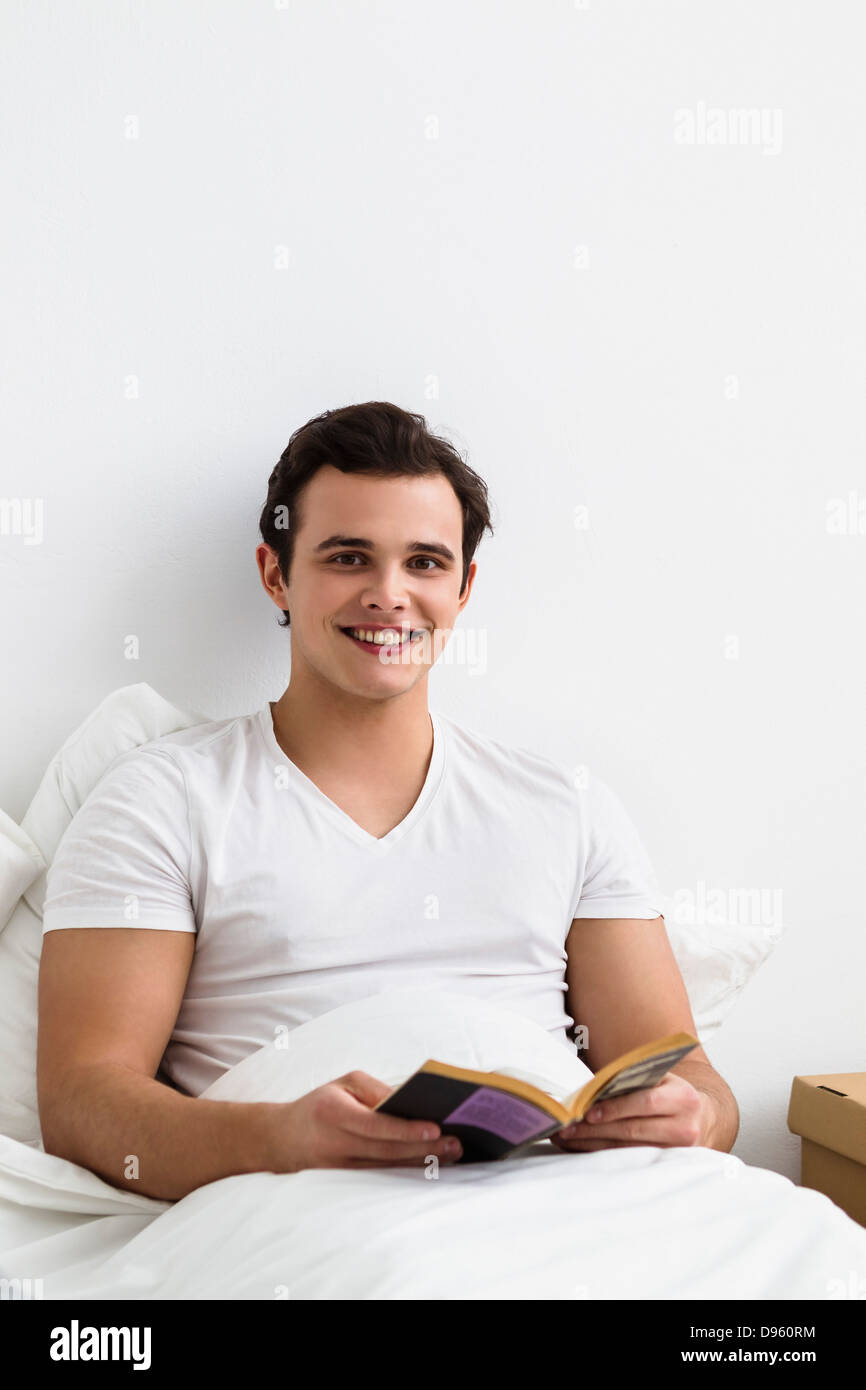 Portrait of young man holding book, smiling Stock Photo - Alamy