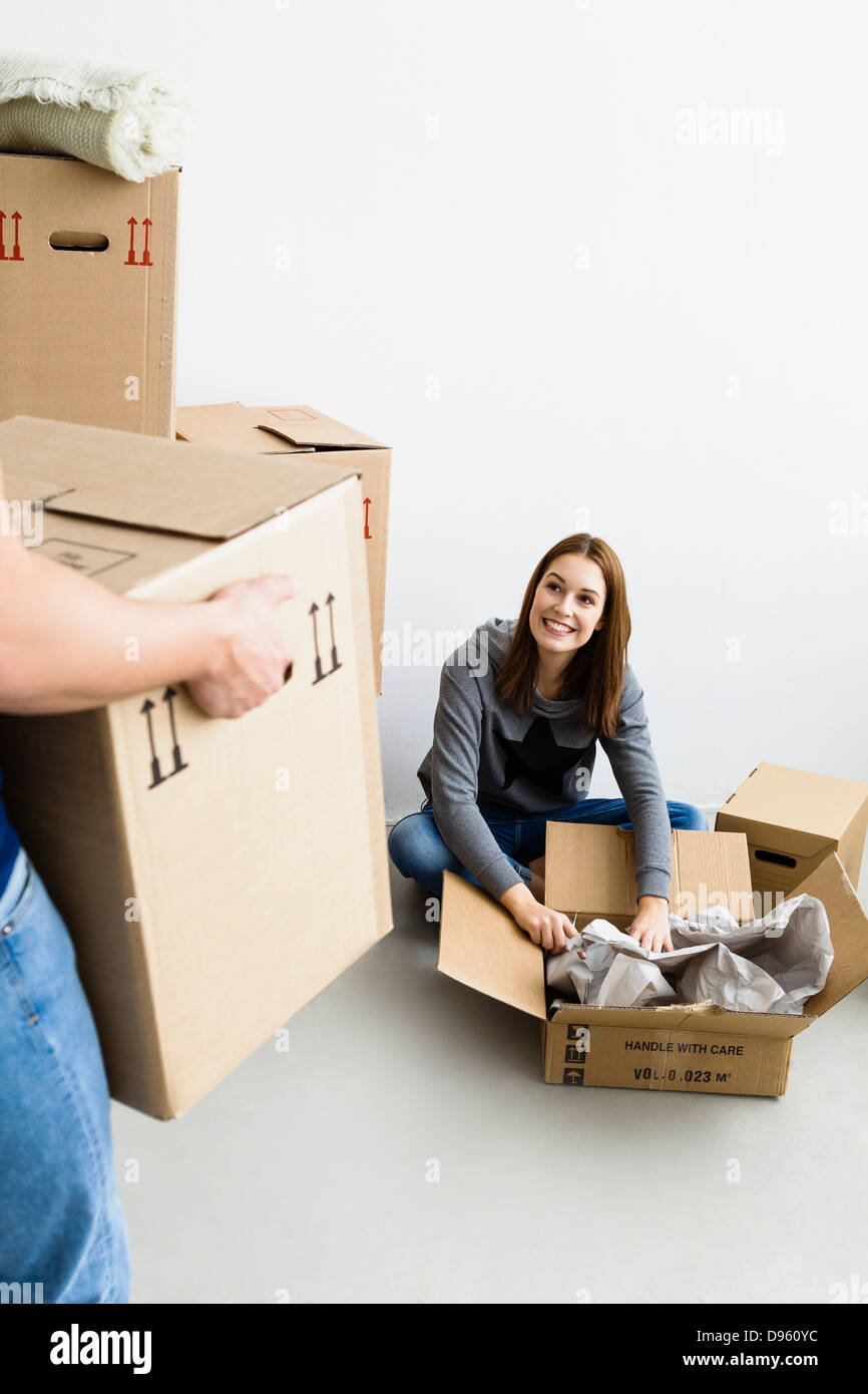 Germany, Munich, Young man holding cardboard box while woman packing ...
