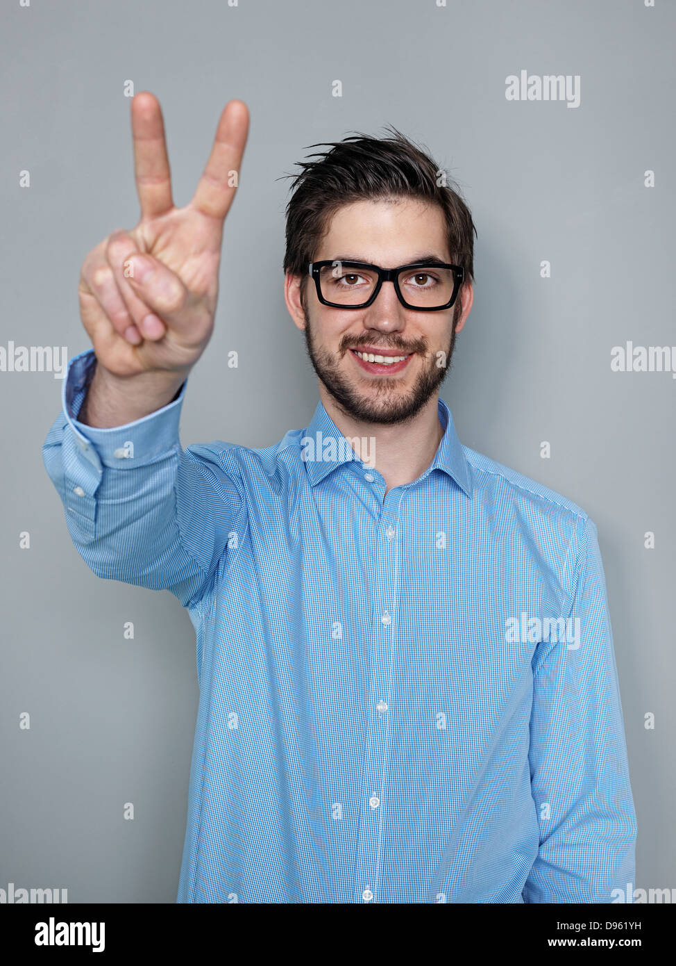Businessman doing peace sign, smiling Stock Photo - Alamy