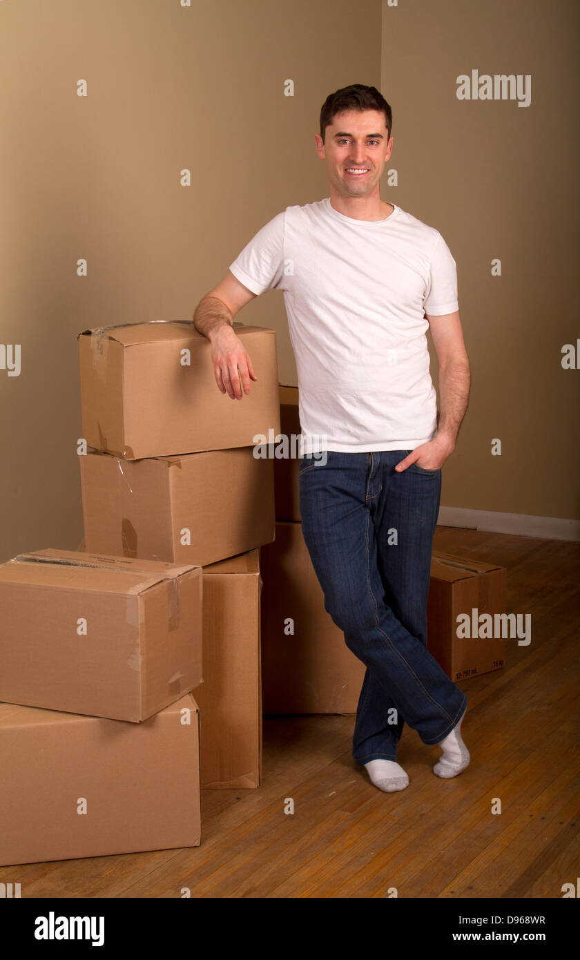 A young man stands with packed up boxes for moving out of his old home ...