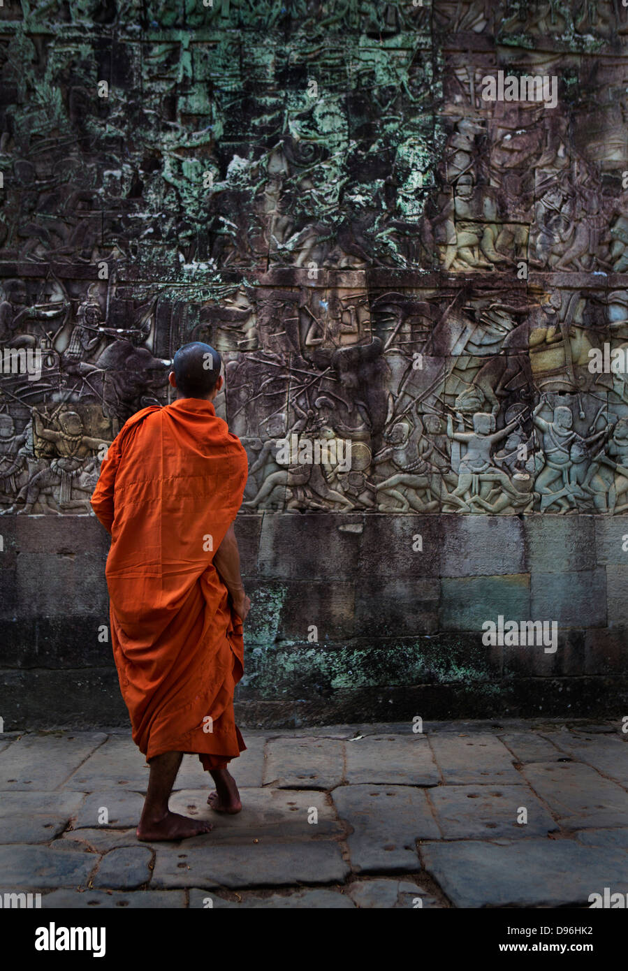 Buddhist monk looking at bas reliefs on the outer wall of the outer ...