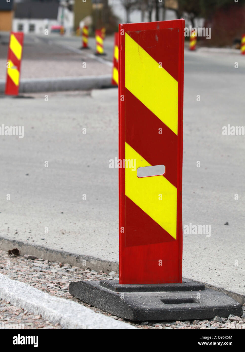 Vertical red and yellow striped caution road sign. Road under ...