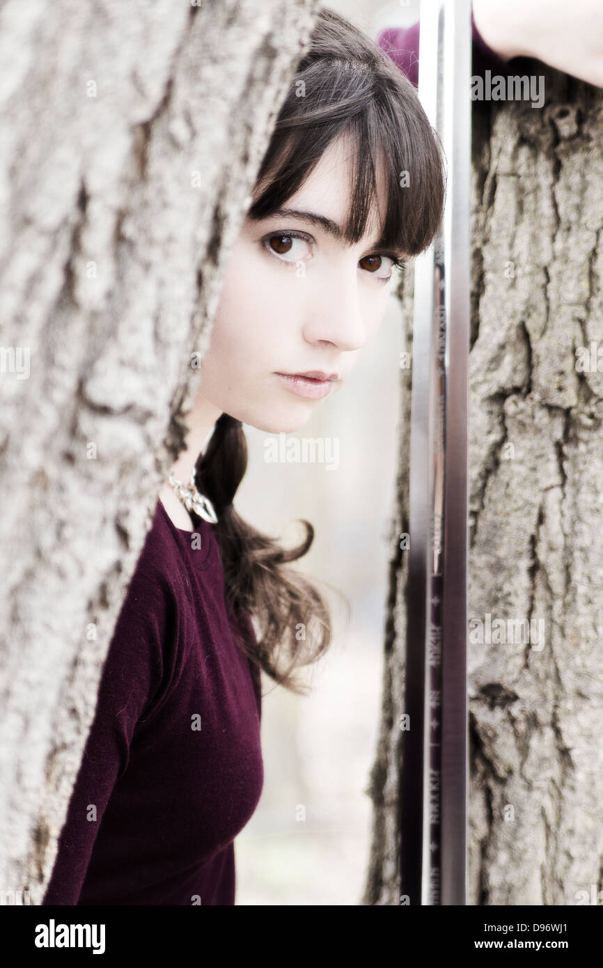 Beautiful young woman with broadsword peers at camera from between two ...