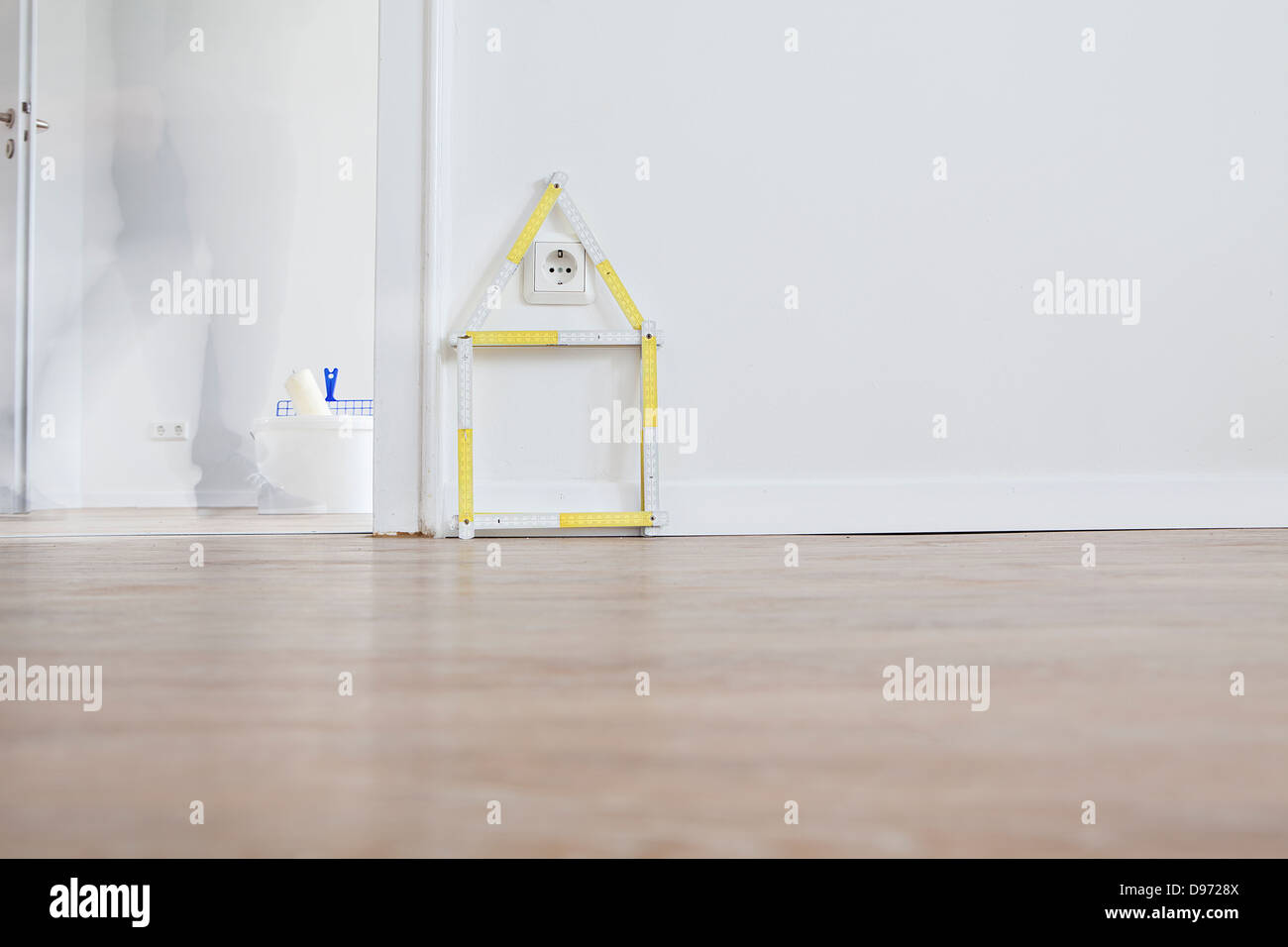 Folded ruler in house shape on wall with person in background Stock ...