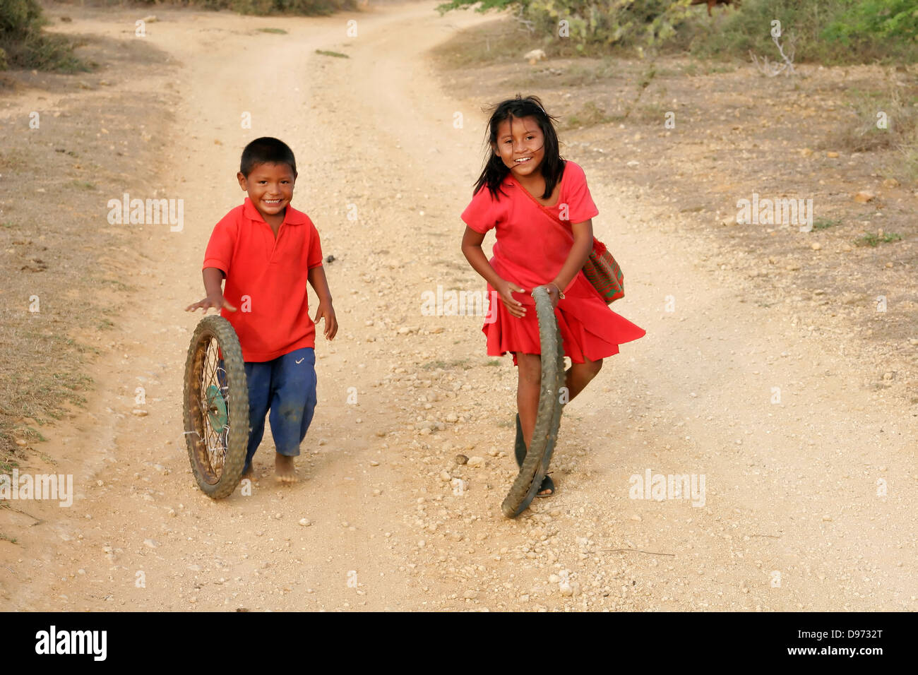 Indigenous Wayuu kids playing on the road with bicycle wheels, Punta ...