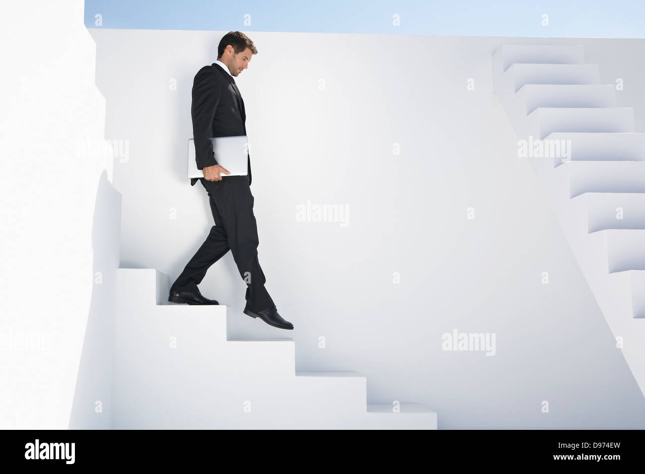Businessman in black suit with laptop moving down stairs Stock Photo ...