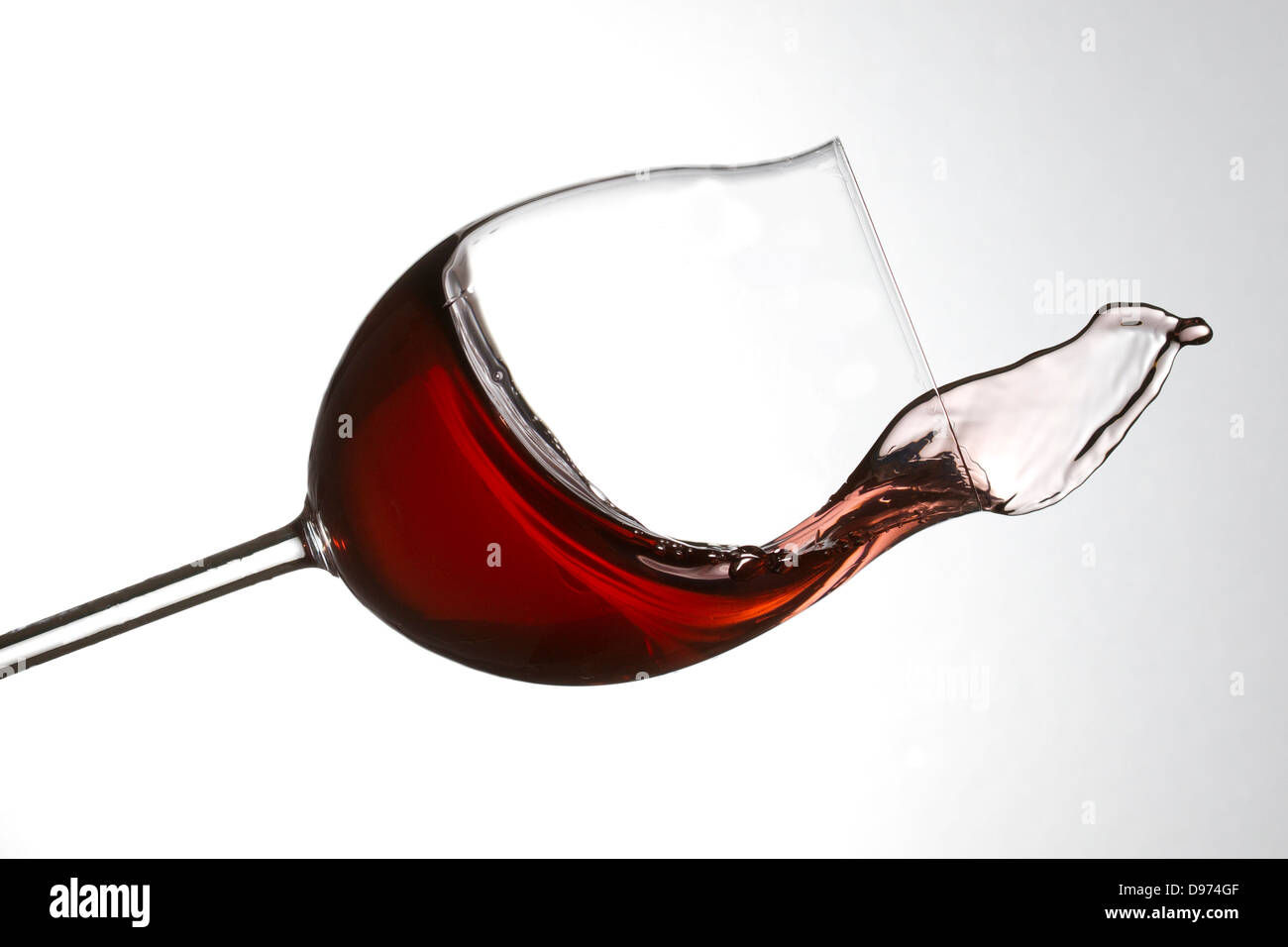 Red wine splashing in glass against white background Stock Photo - Alamy