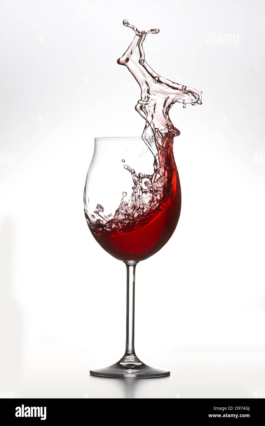 Red wine splashing in glass on white background Stock Photo - Alamy