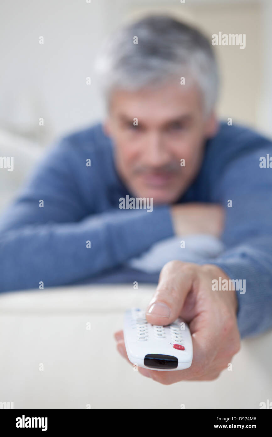 Germany, Bavaria, Munich, Mature man changing channels with remote ...