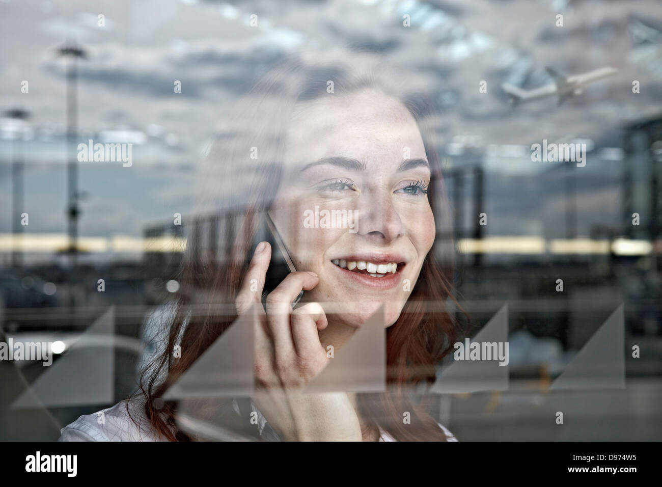 Germany, Cologne, Young woman on phone at airport Stock Photo - Alamy