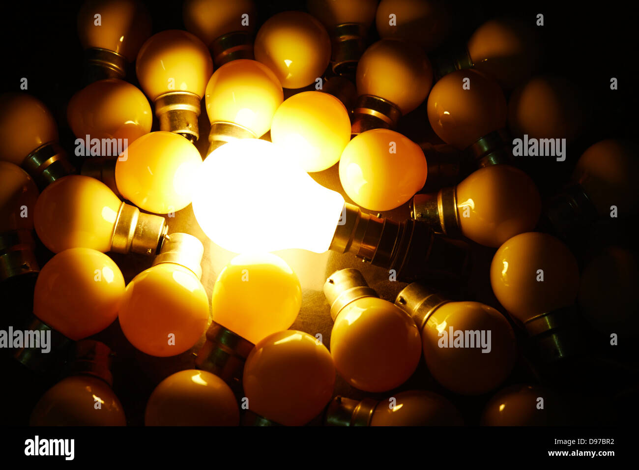 Glowing energy saving bulb surrounded with normal light bulbs Stock ...
