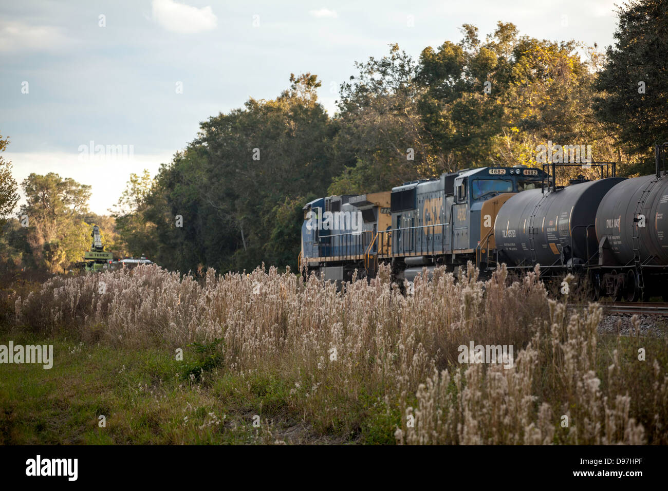 Two CSX engines slowly pull a freight train through a rural area near ...