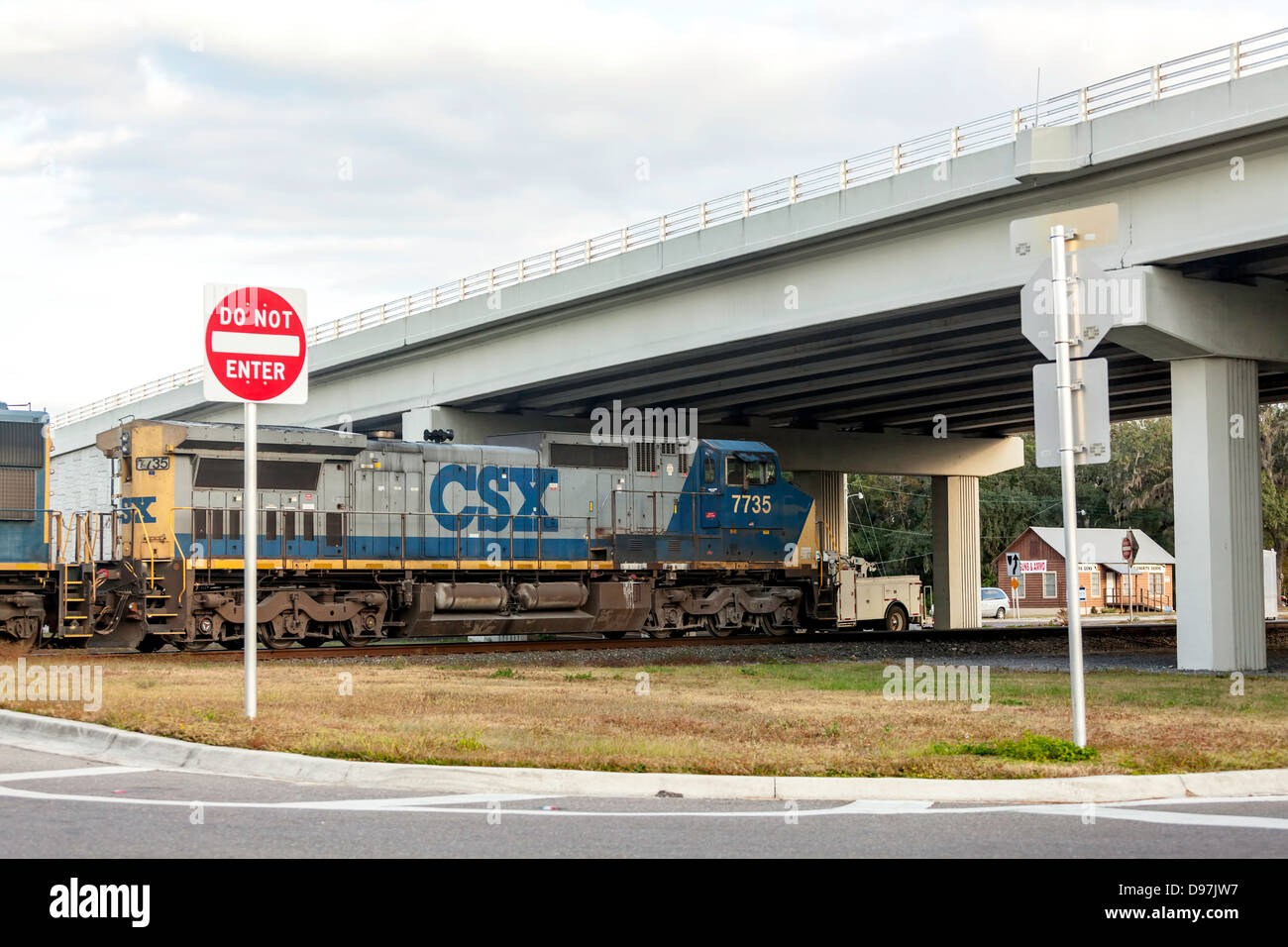 CSX engine 7735 pulling a freight train through a railroad crossing and ...