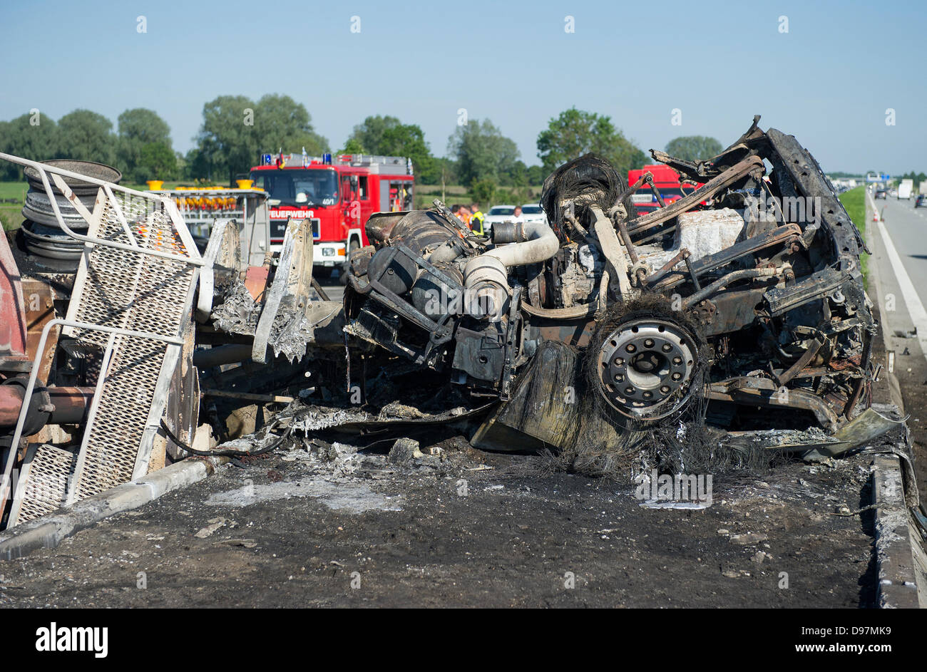 A burned out tractor trailer rests on the median and three lanes of ...