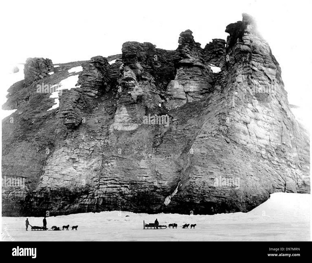 This photo shows a team of dogsledders racing in front of a dramatic ...